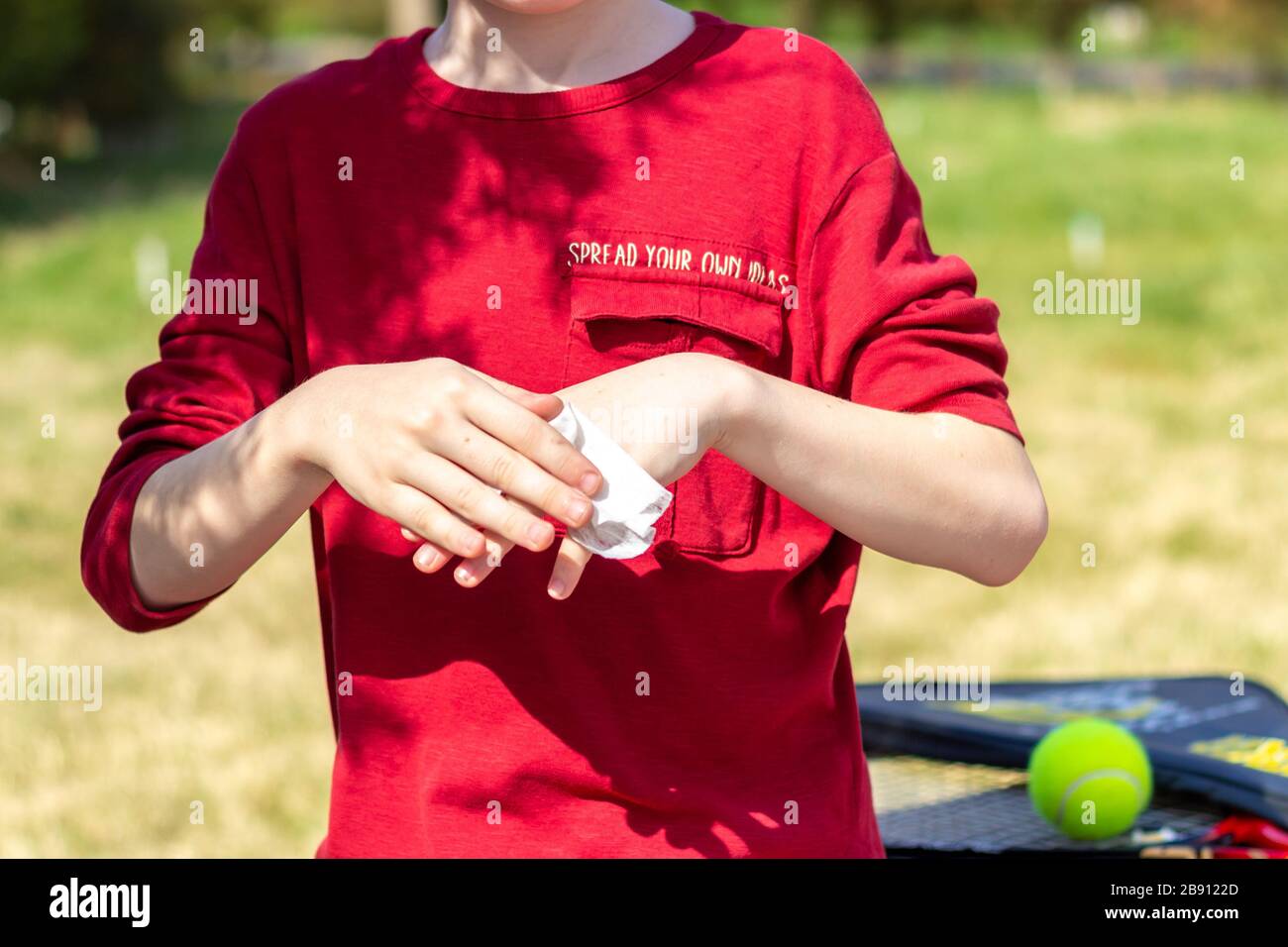 the kid in red t-shirt cleaning his hands with an antibacterial wipe ...