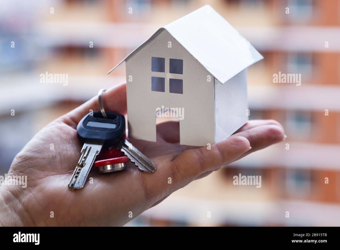 House and keys in hand on the background of a building under ...