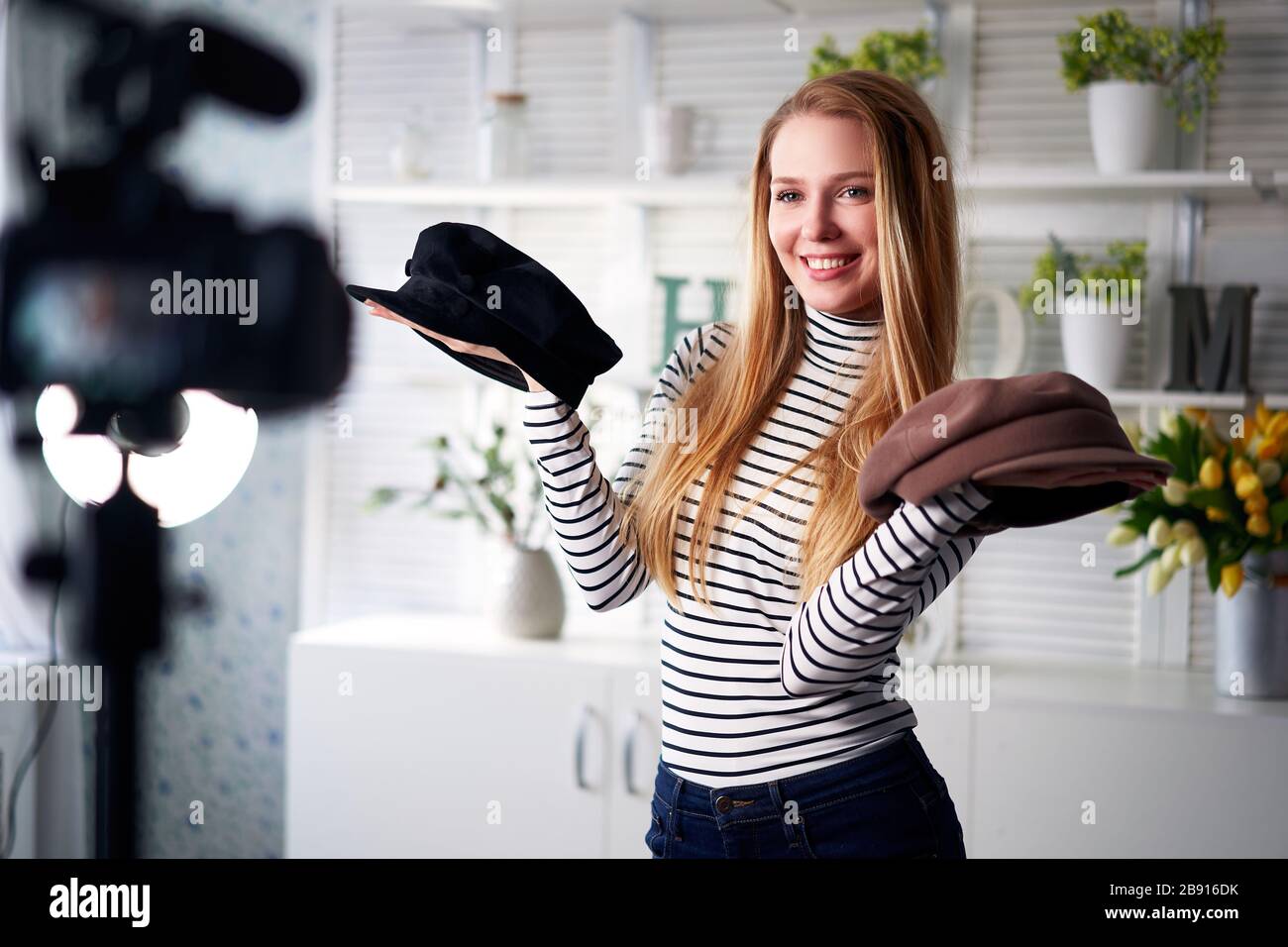 Fashion blogger woman in jeans and turtleneck showing fashionable caps ...