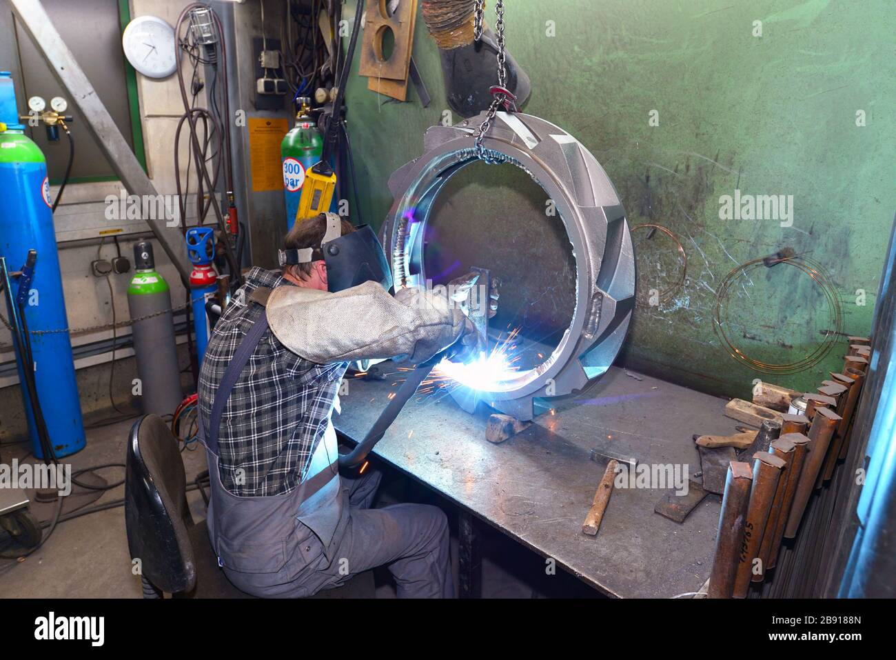 welder at a workplace in metal construction working on a workpiece made ...