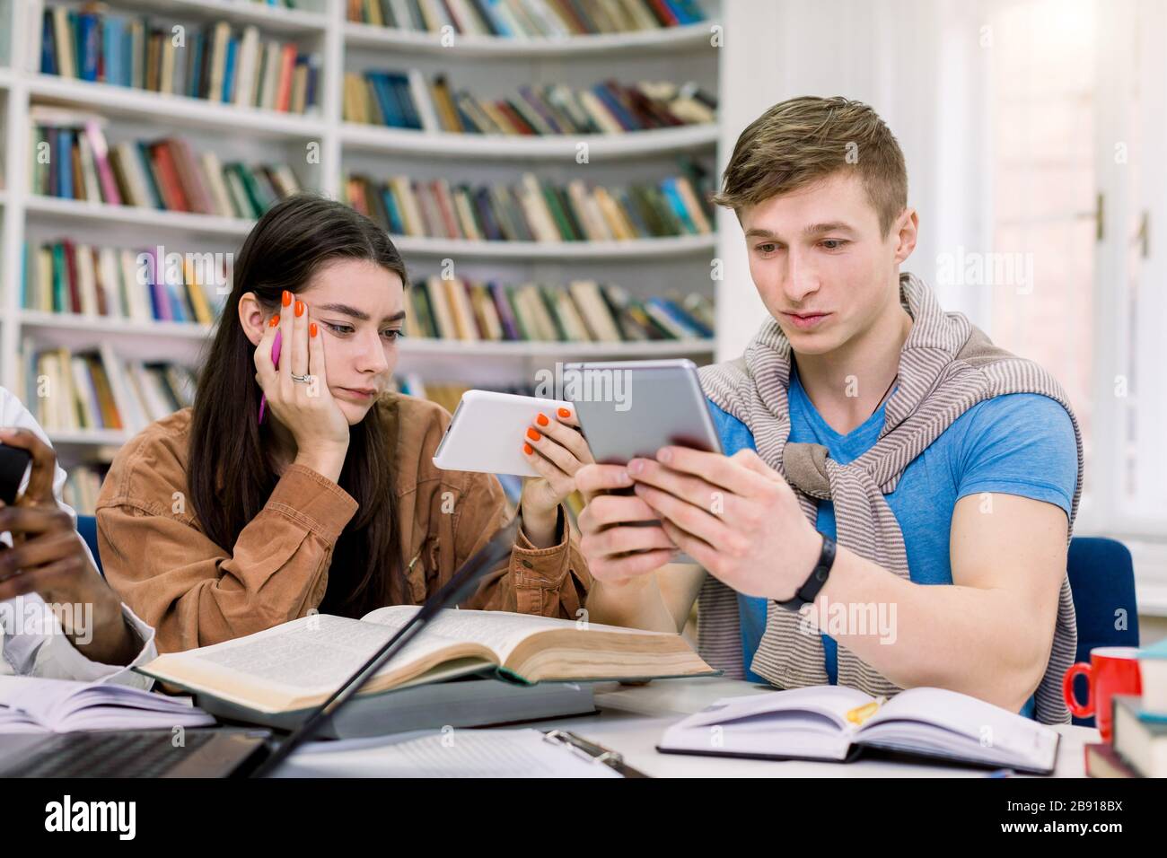 Two male students book tablet library hi-res stock photography and ...