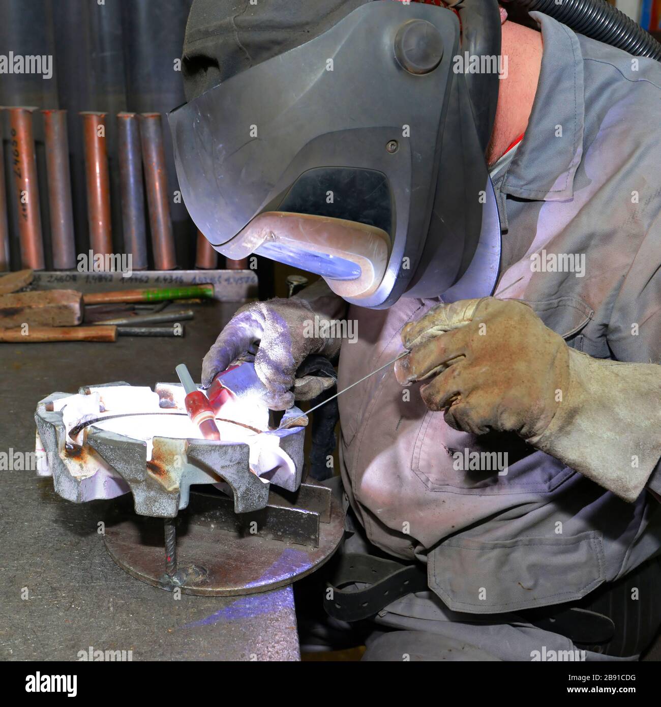 welder at a workplace in metal construction working on a workpiece made ...