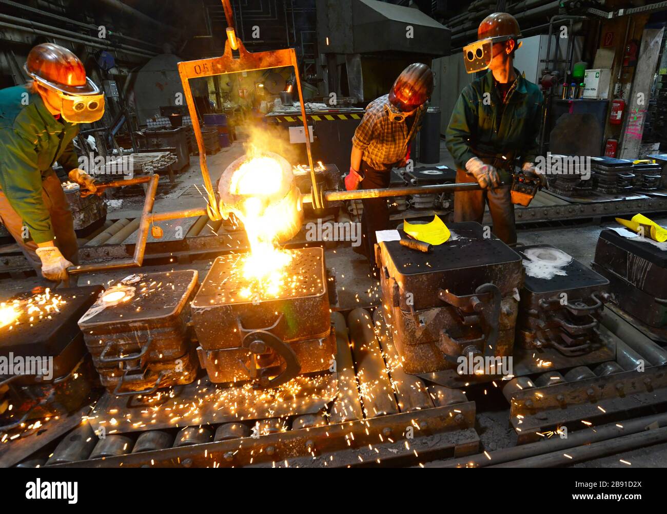 workers in a foundry casting a metal workpiece - safety at work and ...