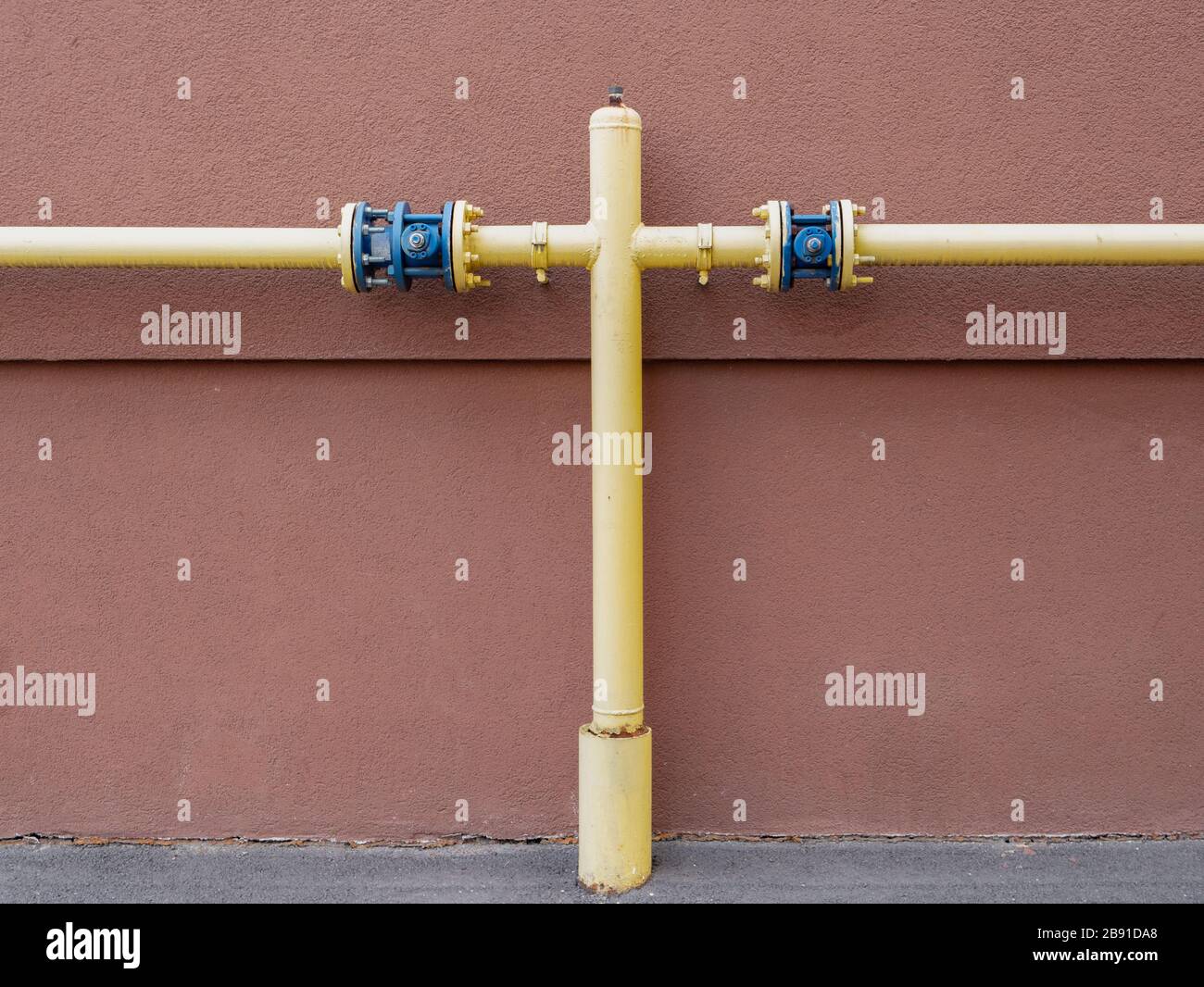 yellow water gas utility pipe branching with painted concrete wall on ...