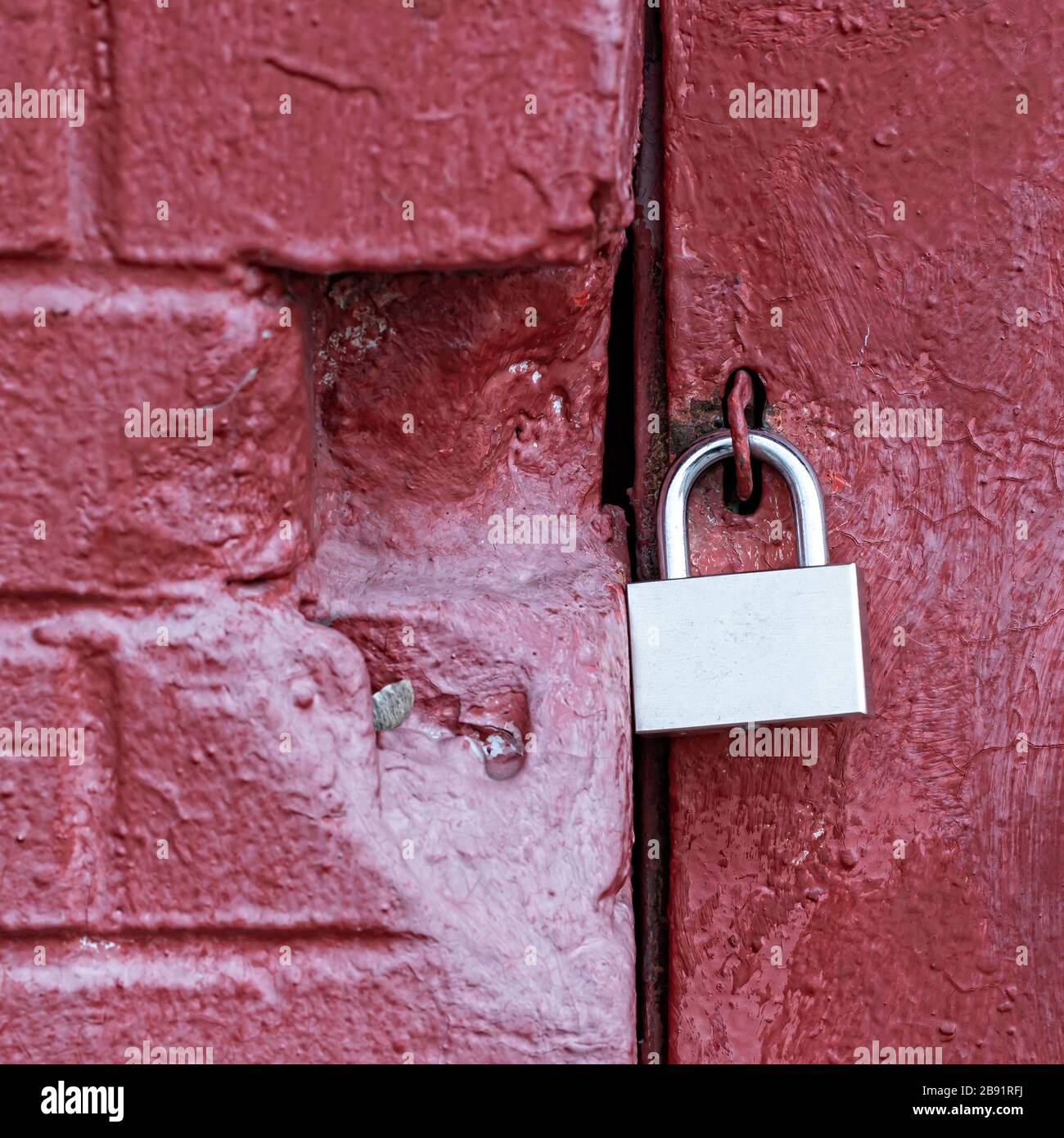 A silver padlock locks the old doors securely. Close- up view. Red ...