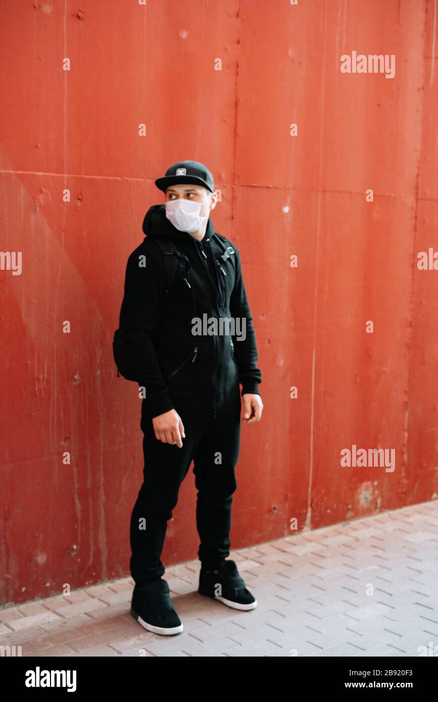 a young man in black sportswear and a baseball cap with a medical mask ...