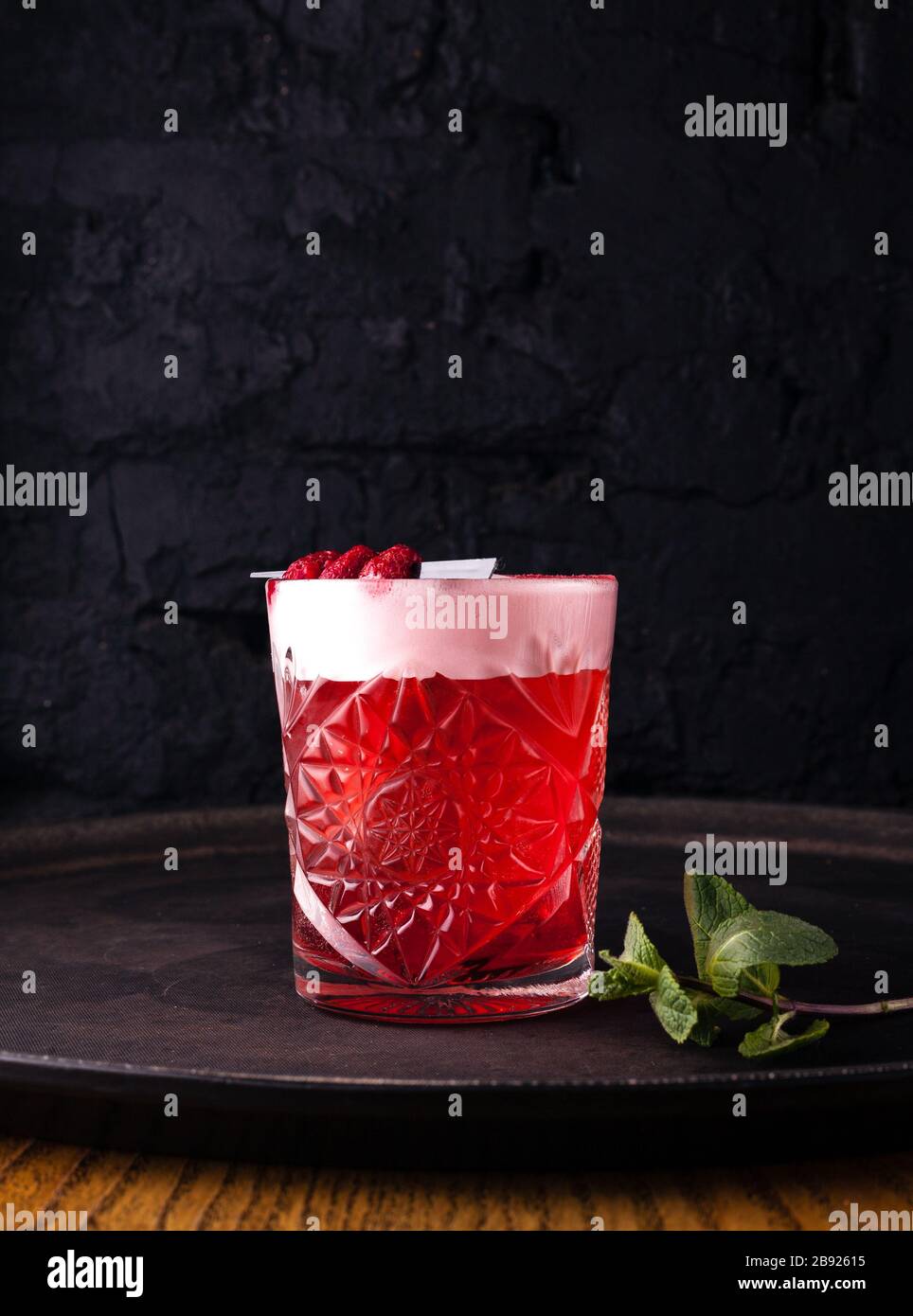 Red, sweet berry cocktail with froth, decorated with raspberries on a ...