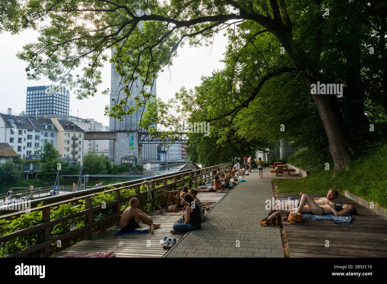 People relax in the shade of trees at a public swimming area (Flussbad ...
