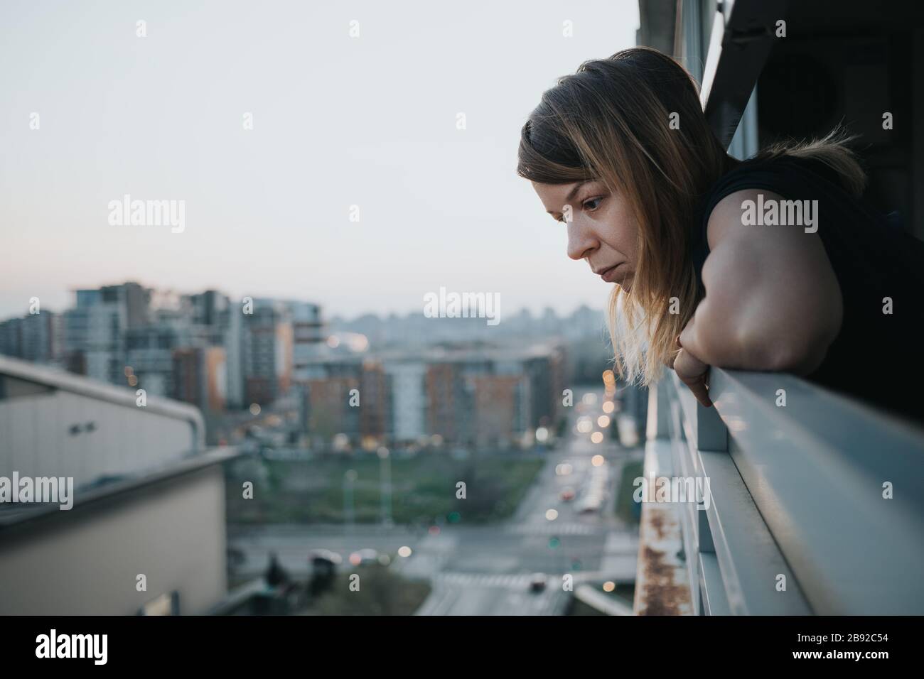 Young sad woman looking outside through balcony of an apartment ...