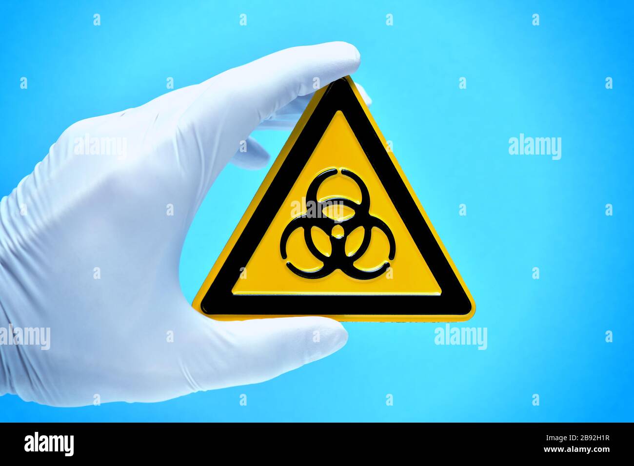 Biology danger sign is held by a hand in the latex glove, symbolic ...