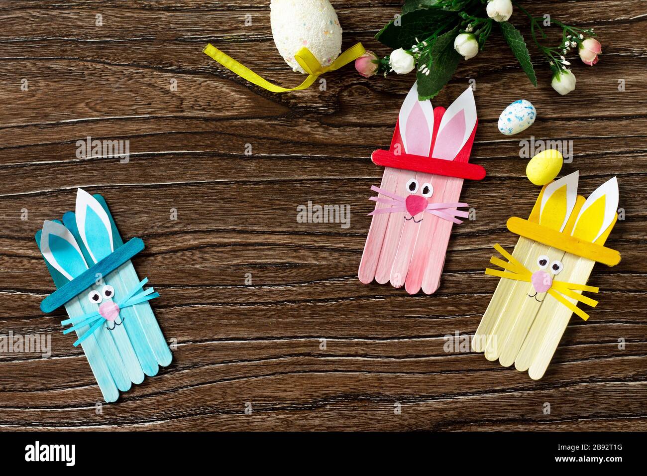 Easter bunny toy gift stics puppets on wooden table. Copy space ...