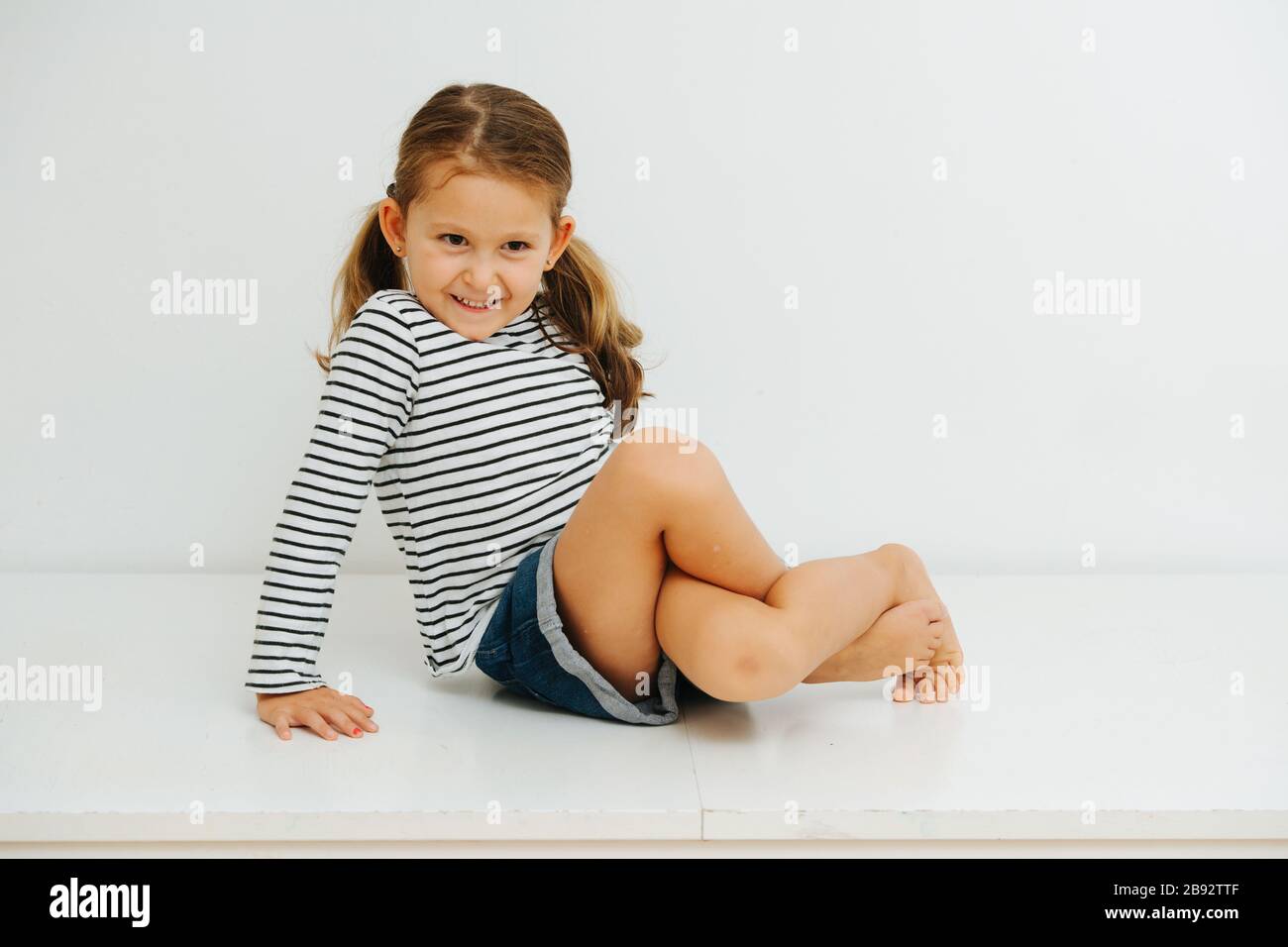 Little girl with pigtails twisting her legs Stock Photo - Alamy