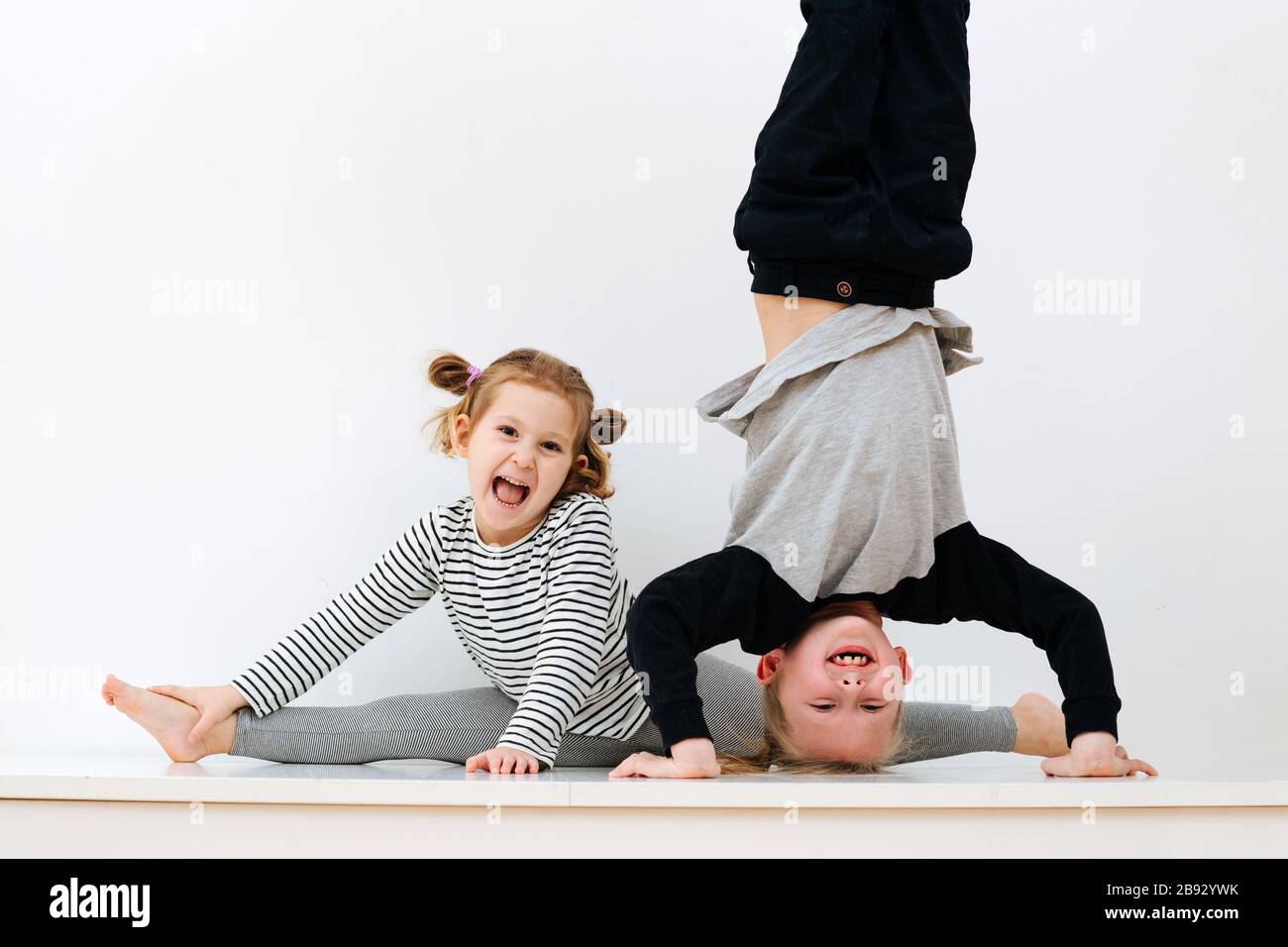 Brother standing on his head and sister sitting on twine Stock Photo ...