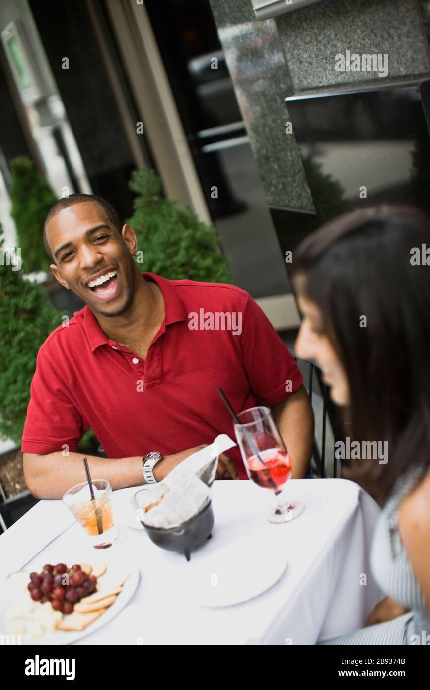 Young man laughing while seated at an outdoor cafe table Stock Photo ...