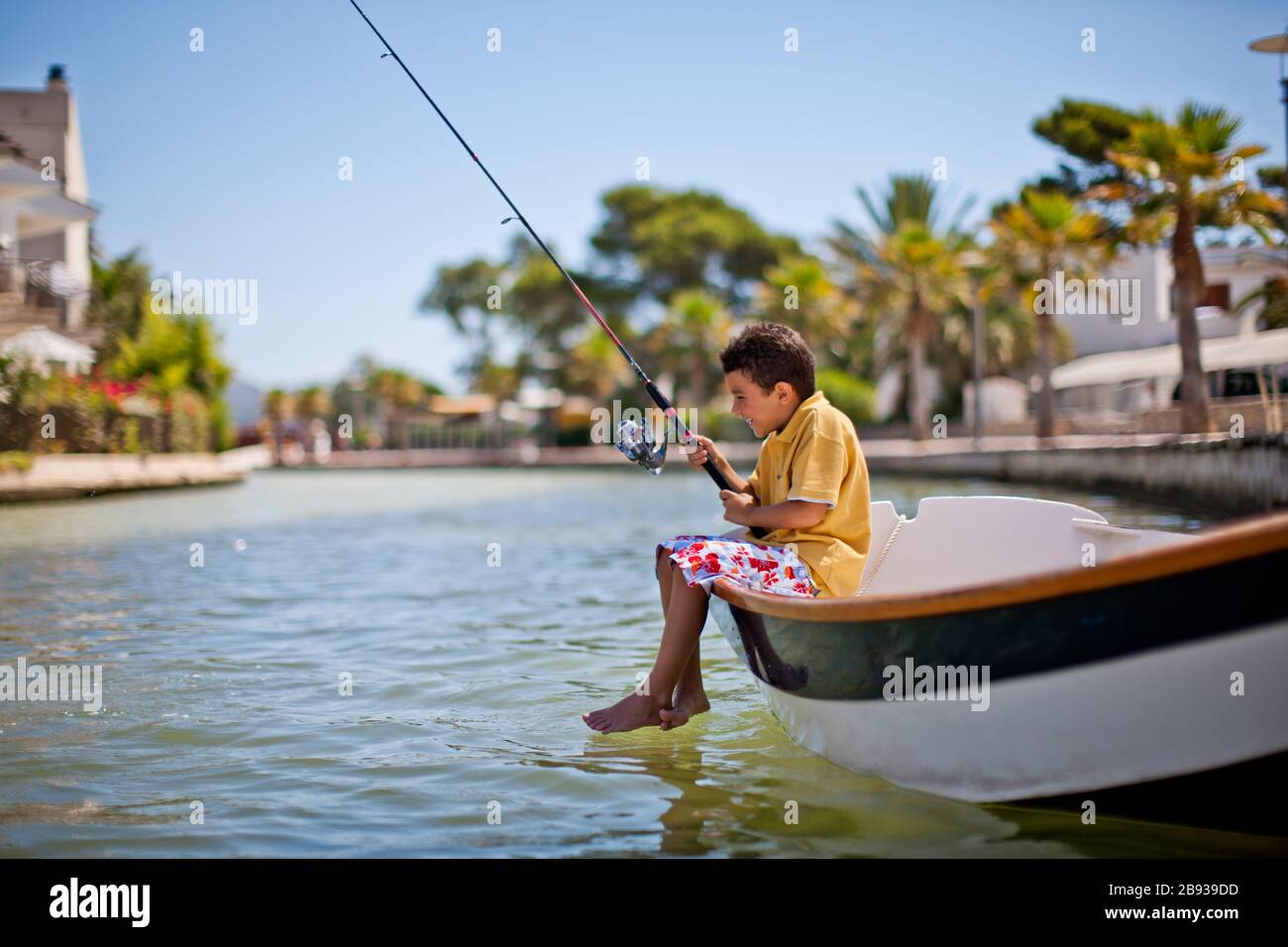 Happy young boy fishing from a small boat in a tropical river Stock ...