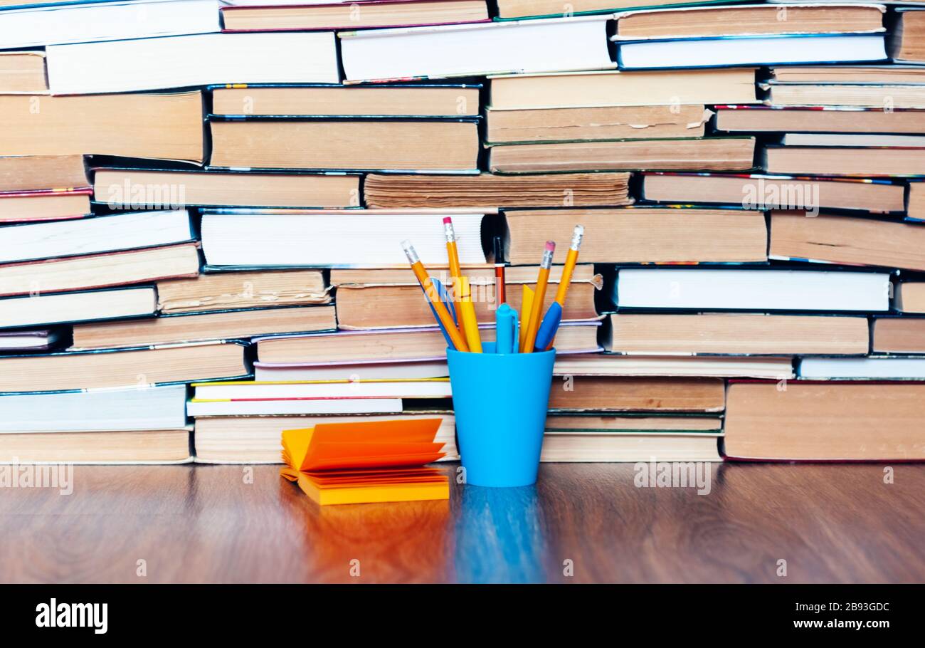 Pencils in holder, note paper and stack of books, school background for ...