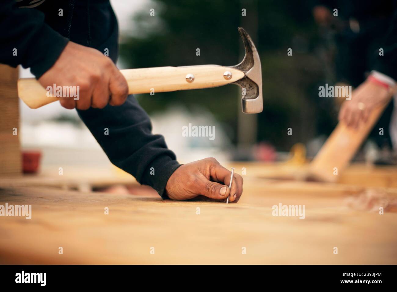 Builder using hammer and nail Stock Photo - Alamy