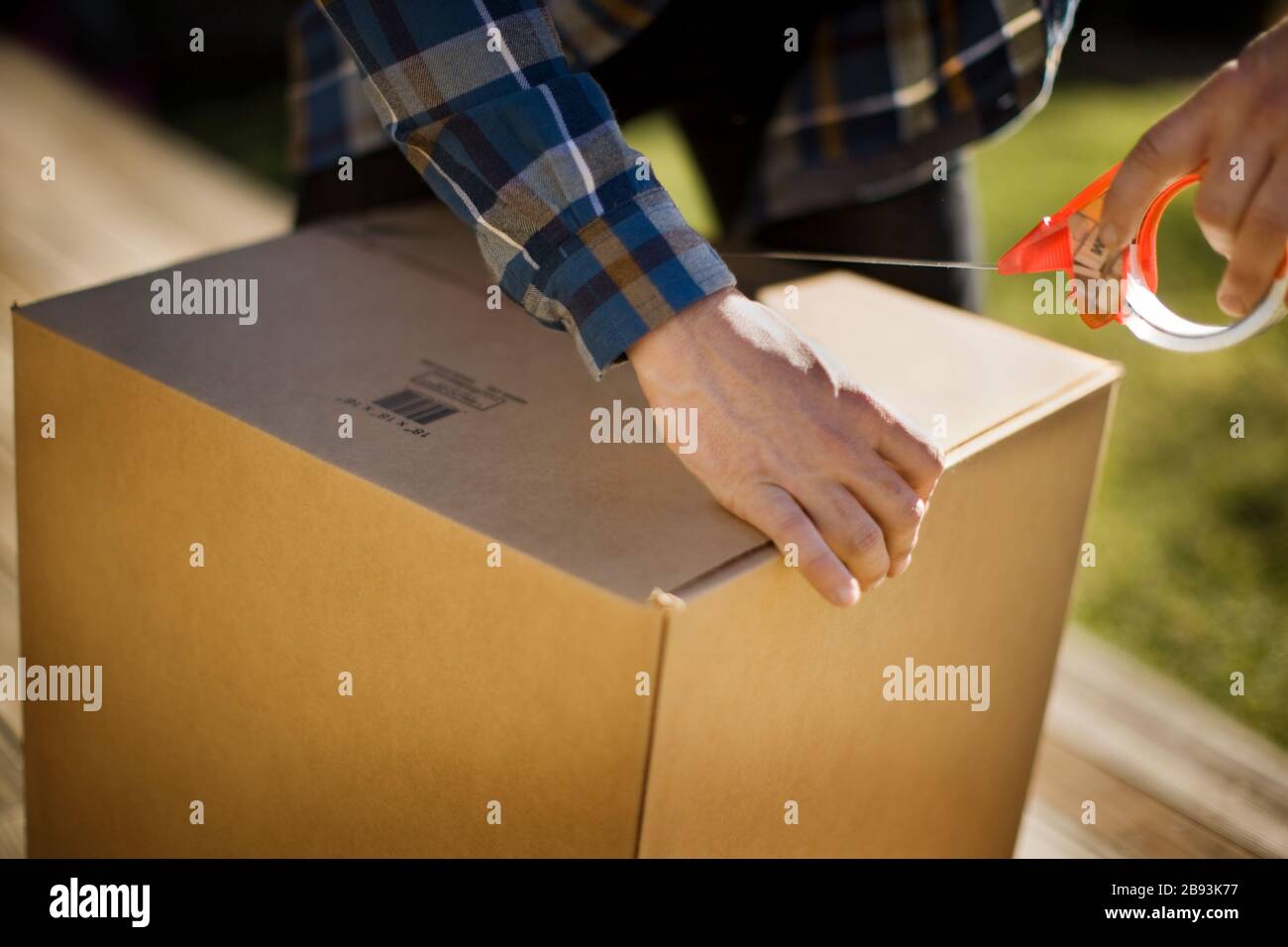 Man taping up a cardboard box Stock Photo - Alamy