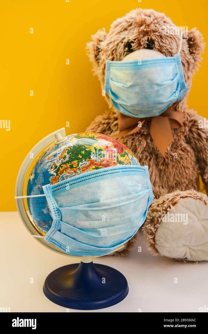 teddy bear toy wearing medical face mask and holding earth world globe ...