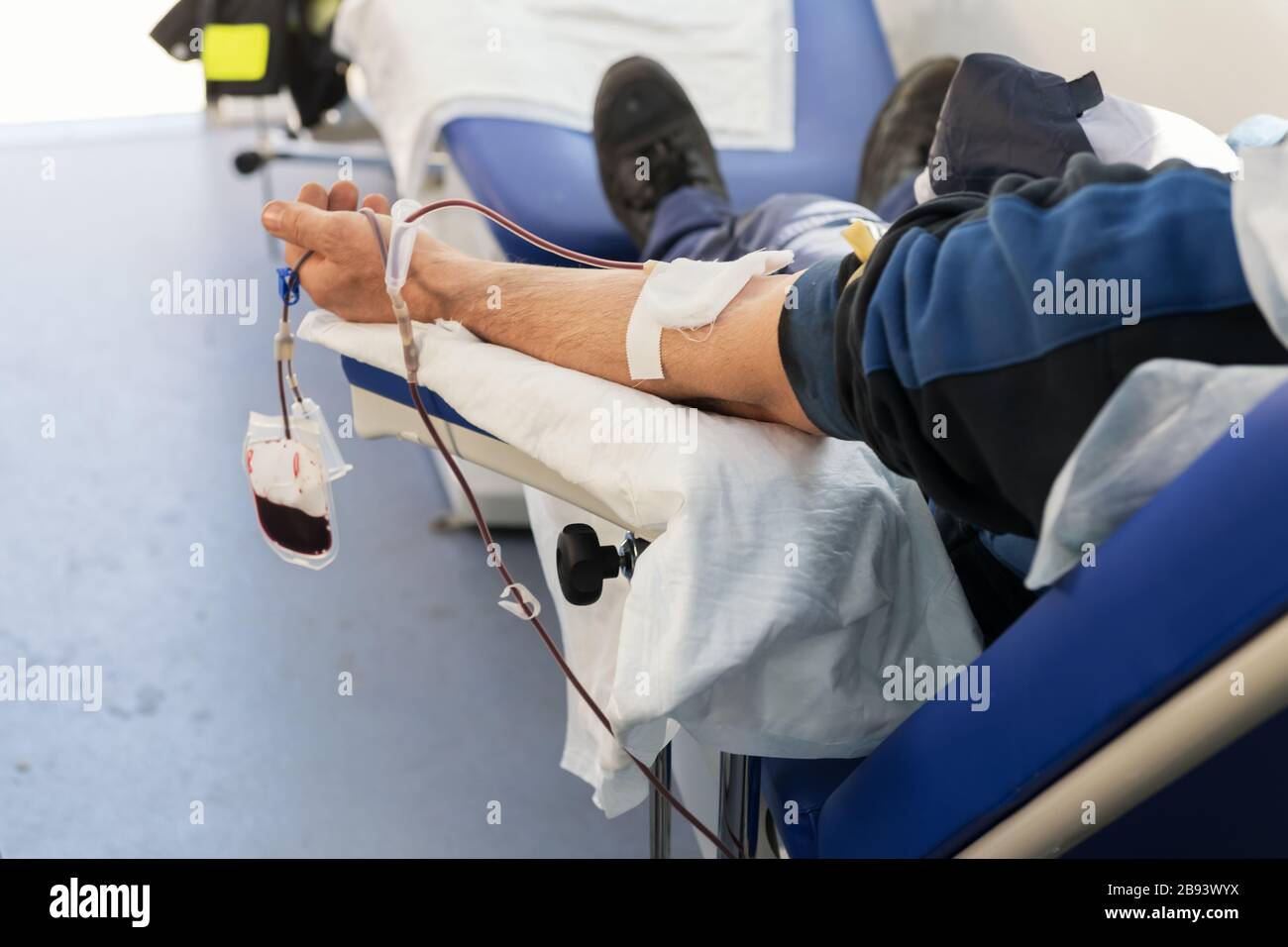 A hand of donor sitting on an armchair in a mobile blood bank during of ...