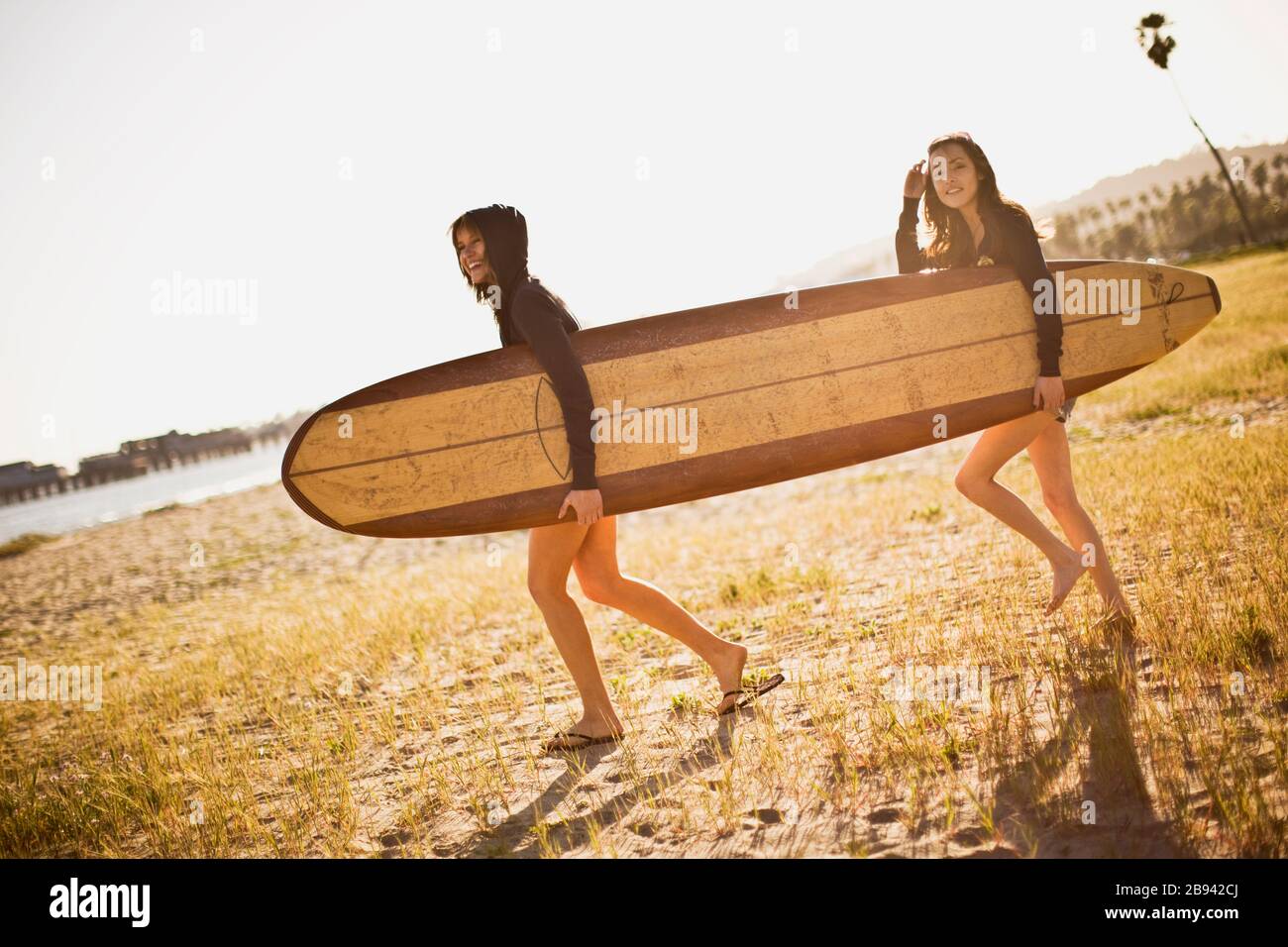 Young women carrying a surfboard on the beach Stock Photo - Alamy