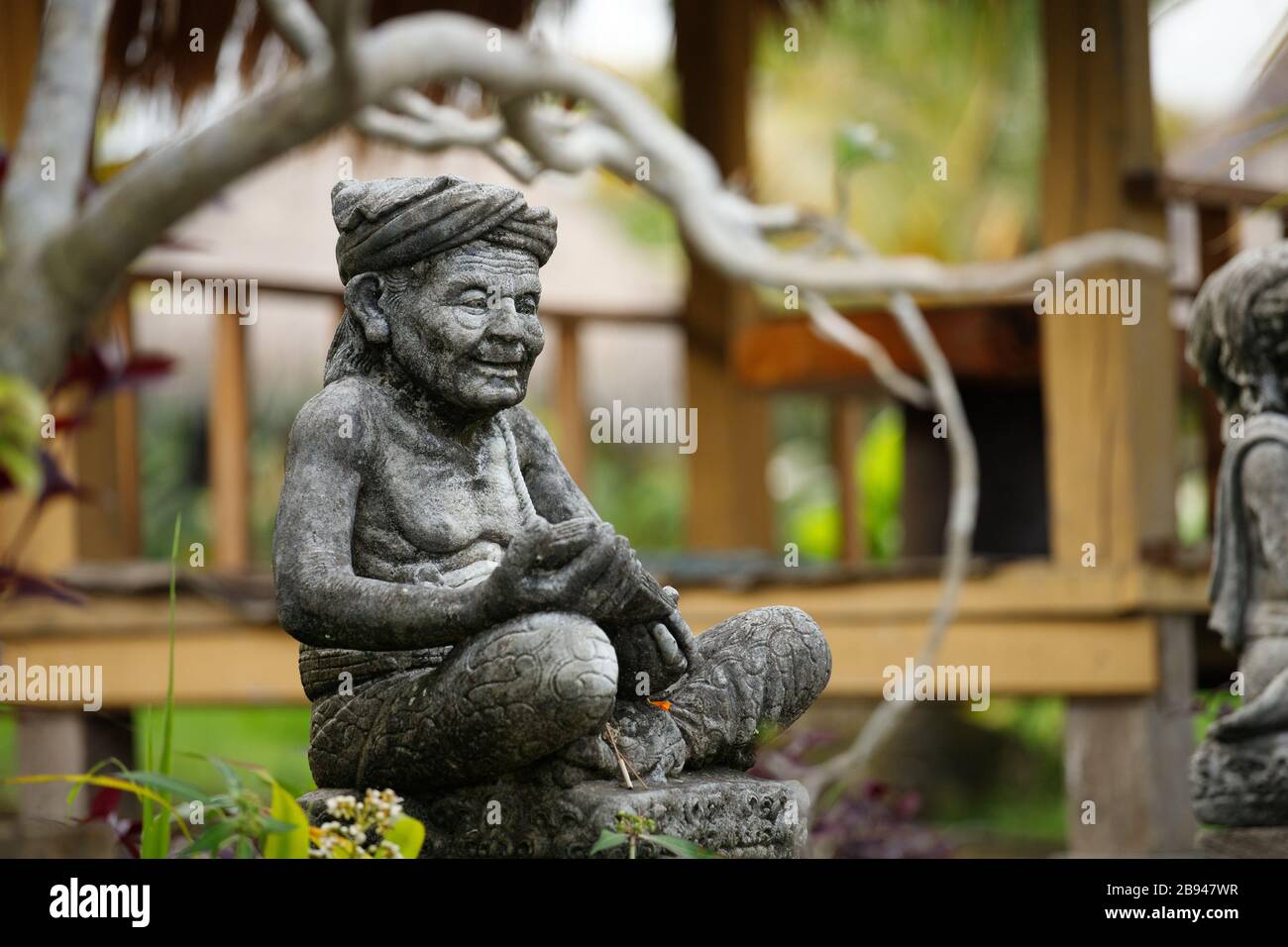 One of many statues at Bali. Framed by a tree branch Stock Photo - Alamy