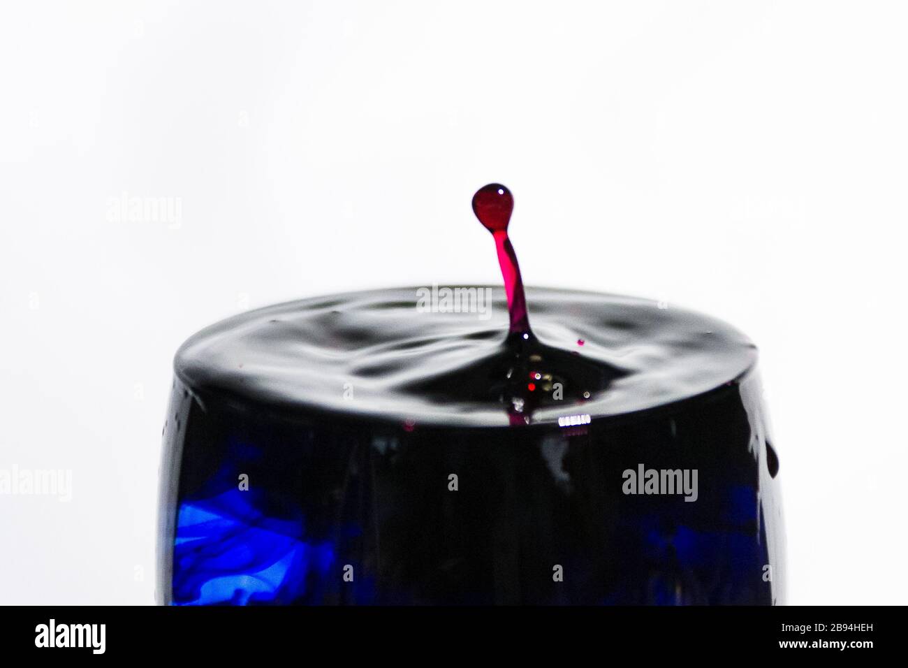 Blue drop splashing into a clear glass of water Stock Photo - Alamy