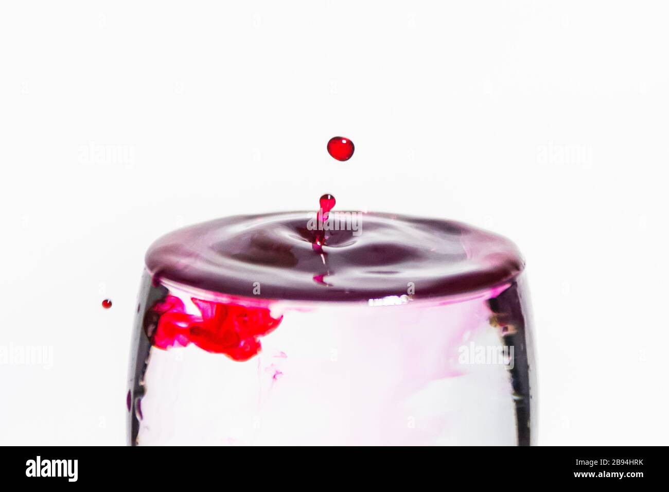Red drop splashing into a clear glass of water Stock Photo - Alamy