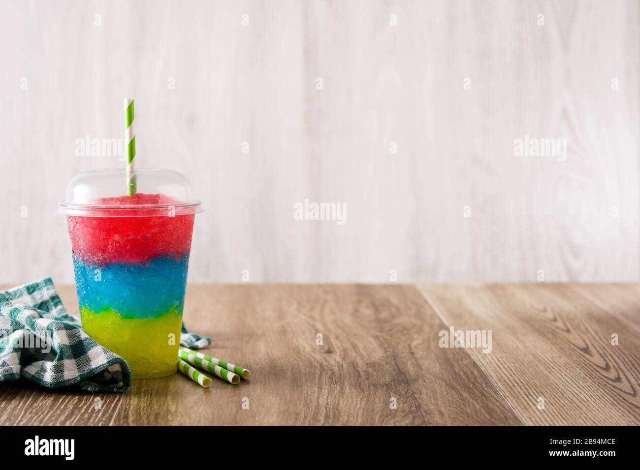 Colorful slushie of differents flavors with straw in plastic cup. Copy ...