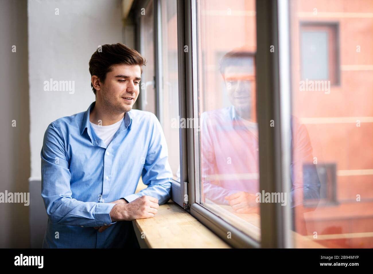 Isolated man standing next to a window in the safety of his own house ...