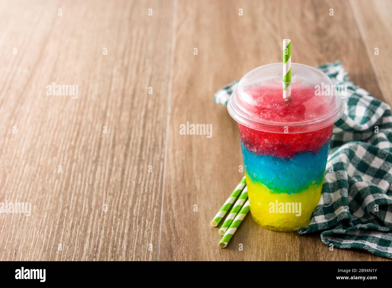 Colorful slushie of differents flavors with straw in plastic cup. Copy ...