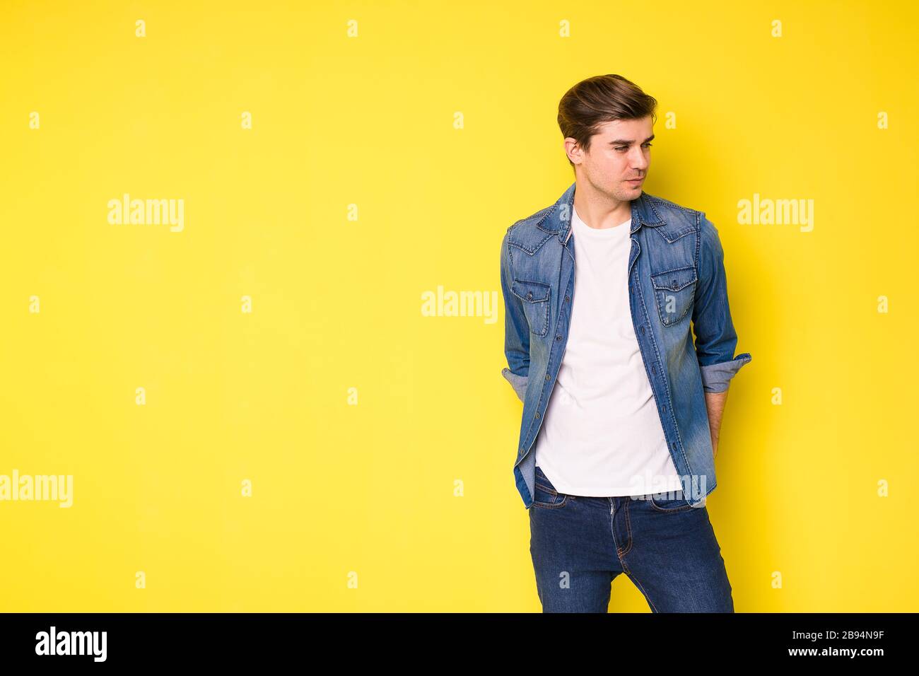 simple and cool guy in jeans looking to side, on yellow background ...