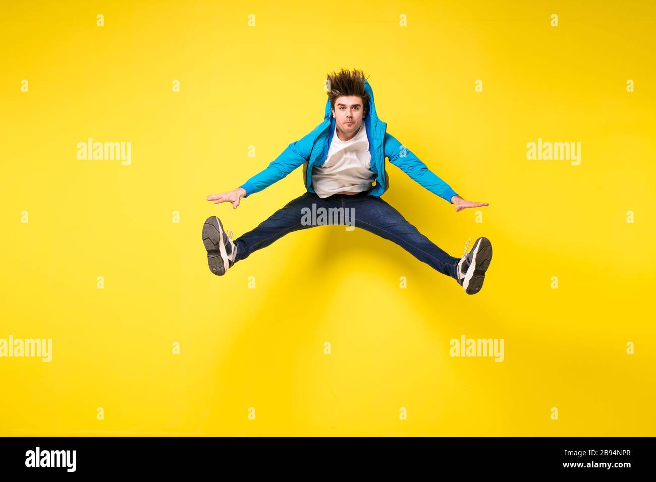 Mid-air shot of handsome young man jumping and gesturing, showing ...