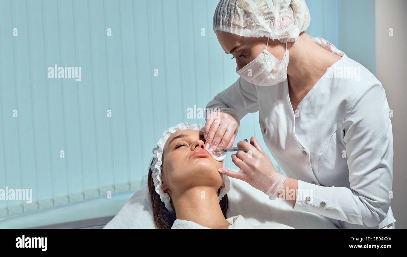 lip shape correction procedure in a cosmetology salon. The specialist ...