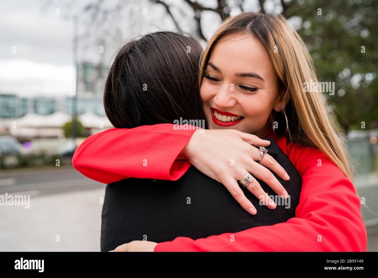 Portrait of two young friends hugging each other outdoors at the street ...