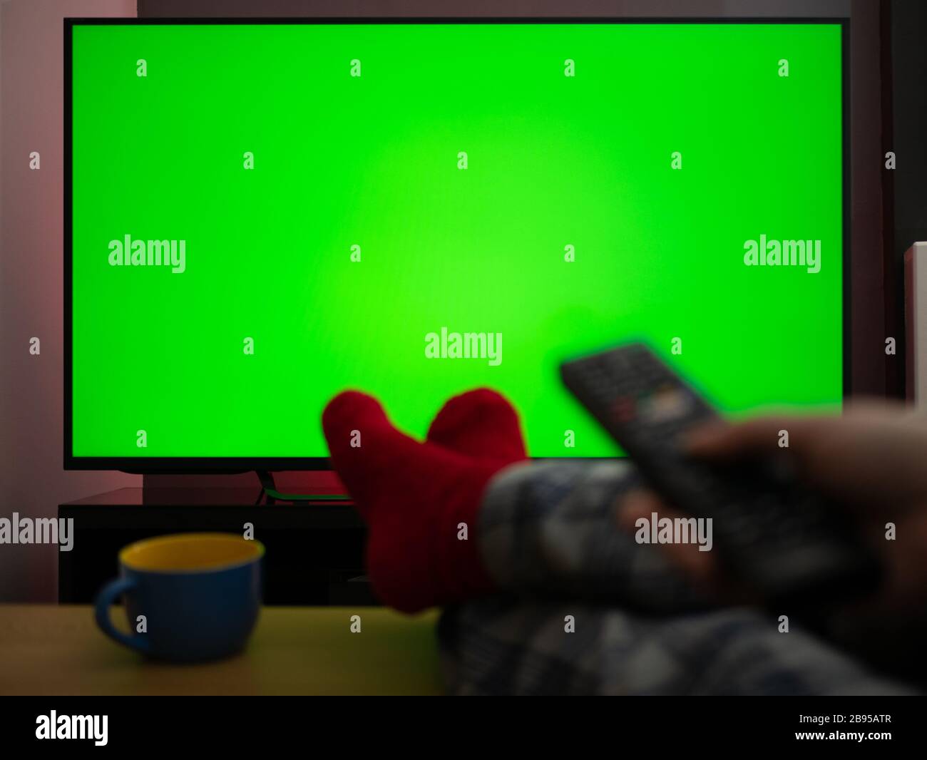 Television chroma key green screen with feet up at home with remote ...