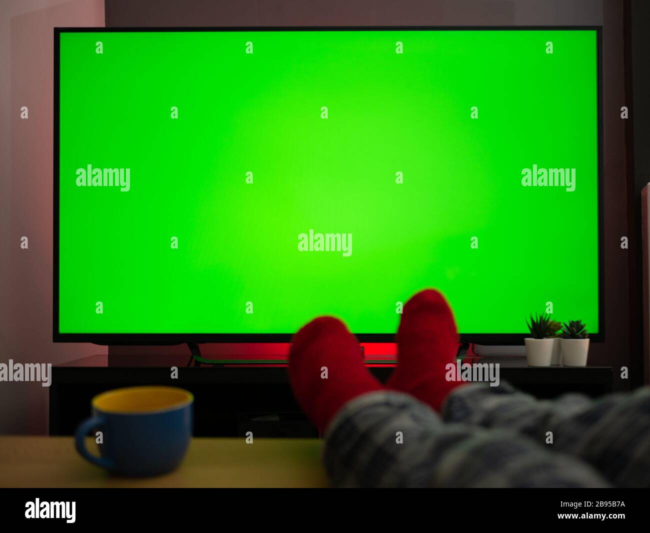 feet up on the table in front of green screen tv televison chroma key ...
