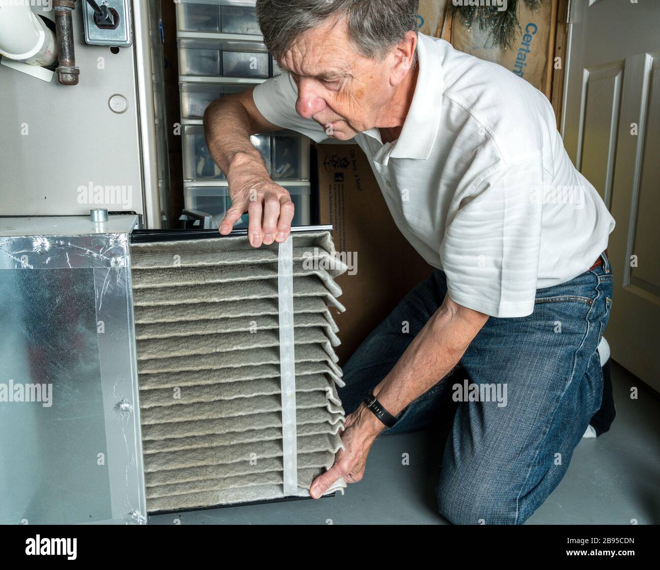 Senior caucasian man changing a folded dirty air filter in the HVAC ...