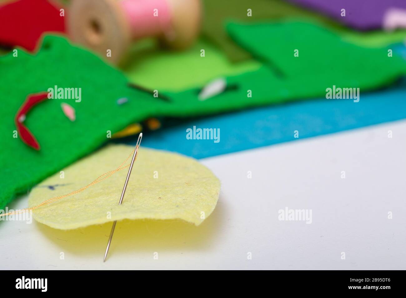 Colored felt, thread, needles and scissors on the white table Stock ...