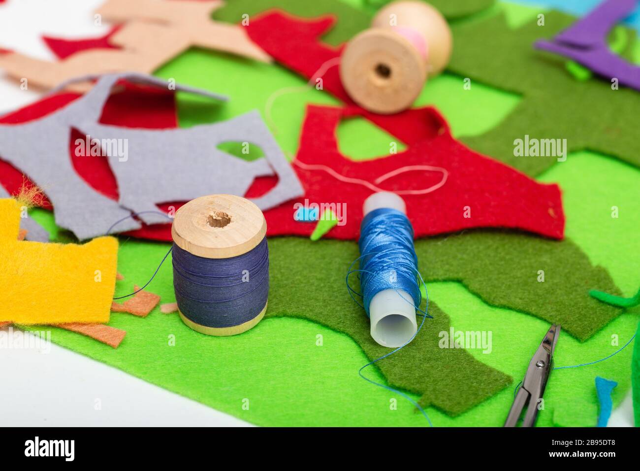 Colored felt, thread, needles and scissors on the white table Stock ...