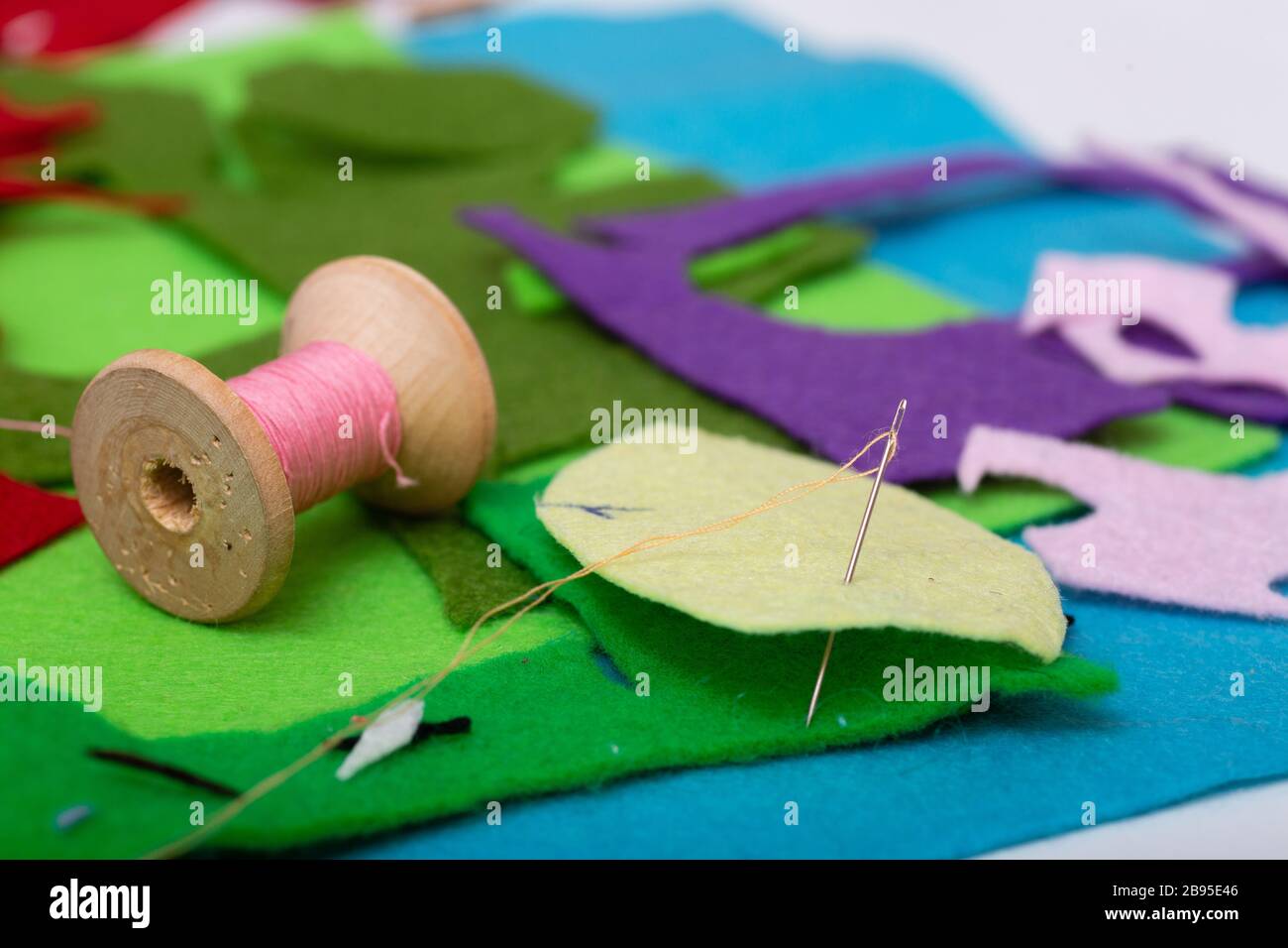Colored felt, thread, needles and scissors on the white table Stock ...