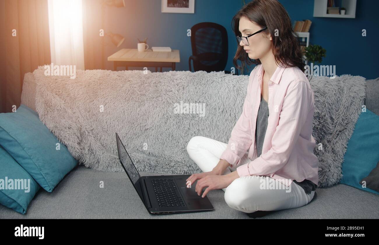 Lady using laptop on couch Stock Photo - Alamy