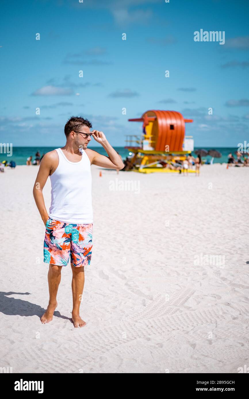 Miami beach Florida, young men on the beach with colorful lifeguard hut ...