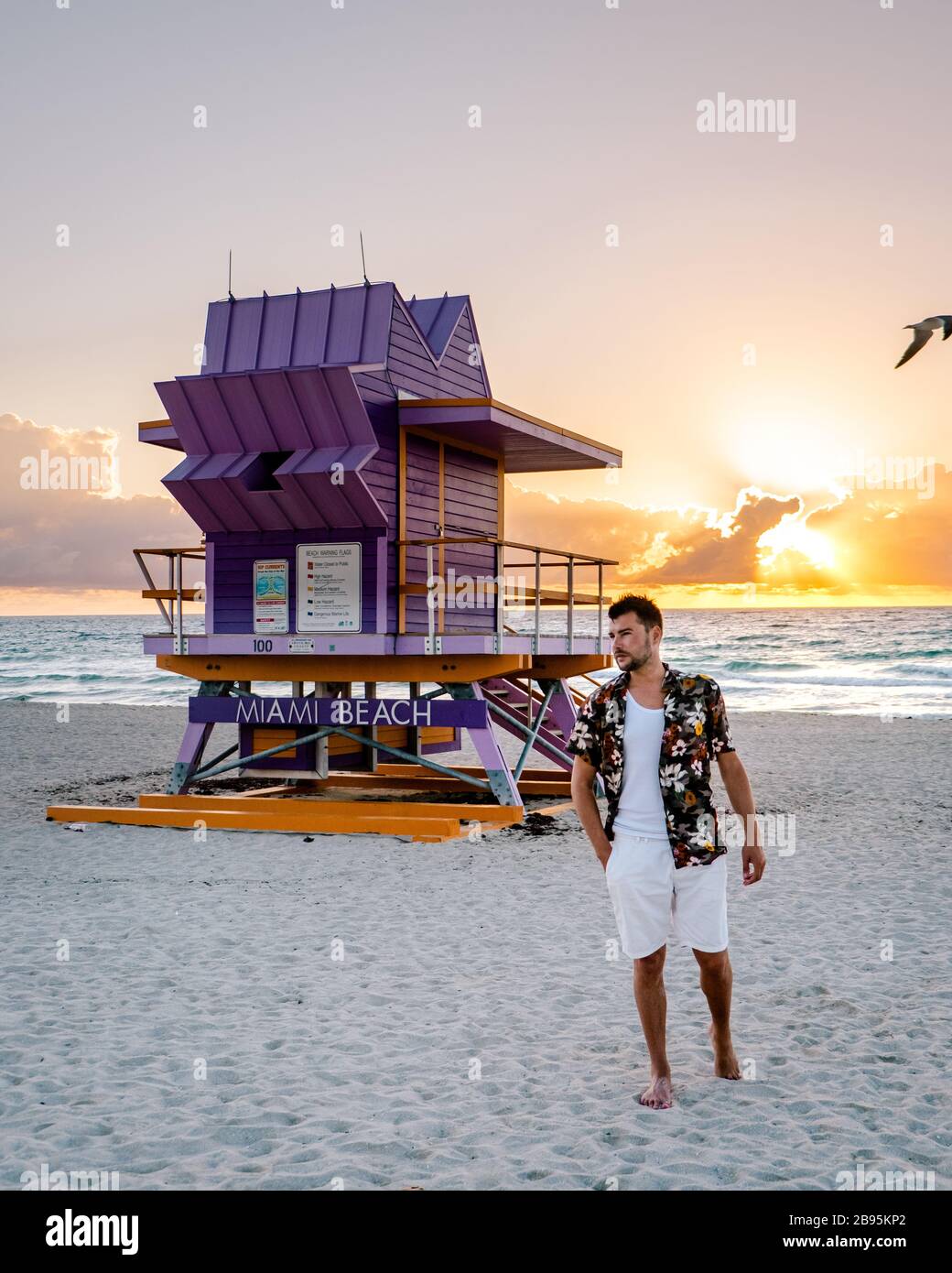 Miami beach Florida, young men on the beach with colorful lifeguard hut ...