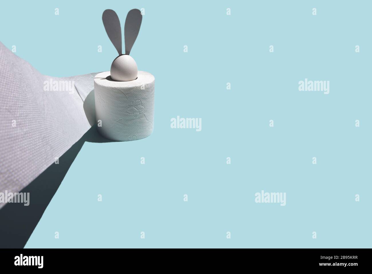 White egg with hare ears in a roll of toilet paper. Hard shadow on a ...