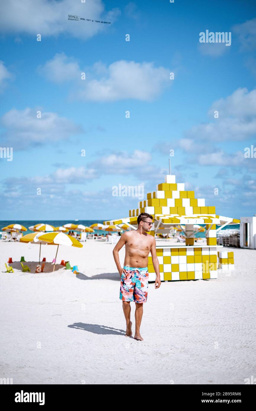 Miami beach Florida, young men on the beach with colorful lifeguard hut ...