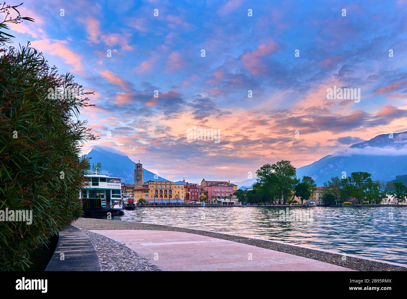 View of the beautiful Riva del Garda town at sunset with a red sky ...