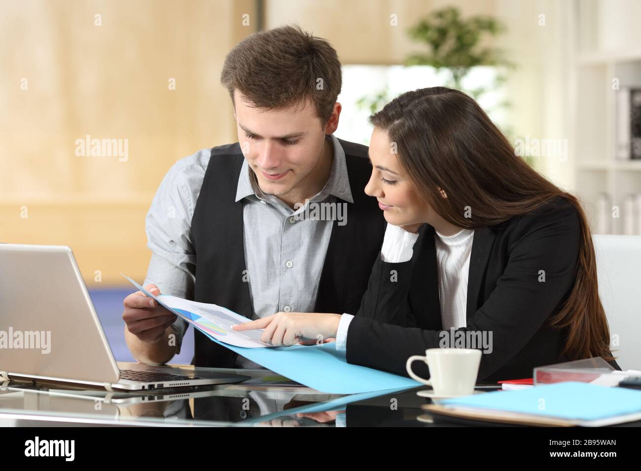 Two concentrated coworkers checking paper informs together at office ...