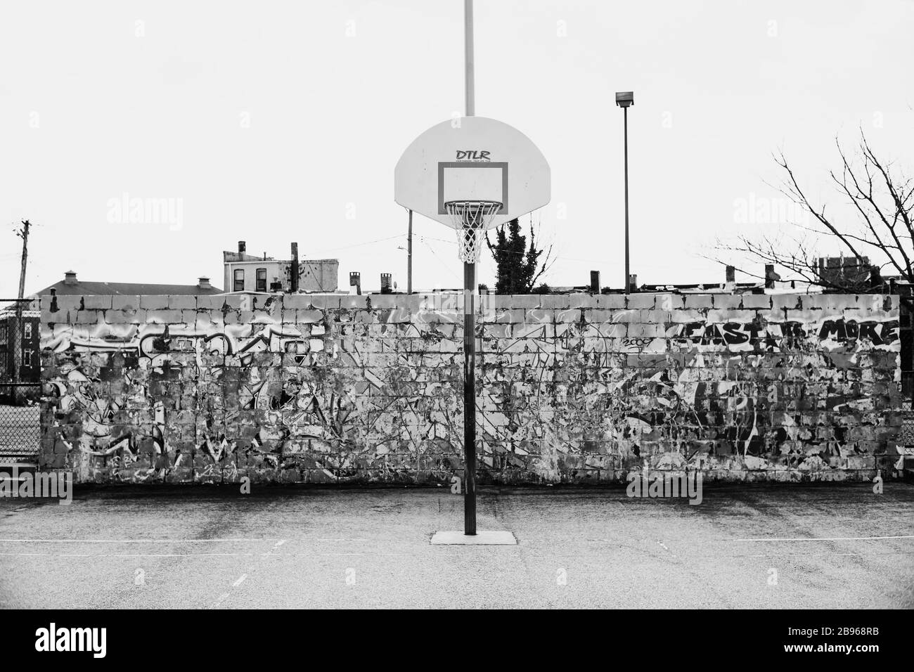 Black and White Vacant basketball court with graffiti covered wall in ...