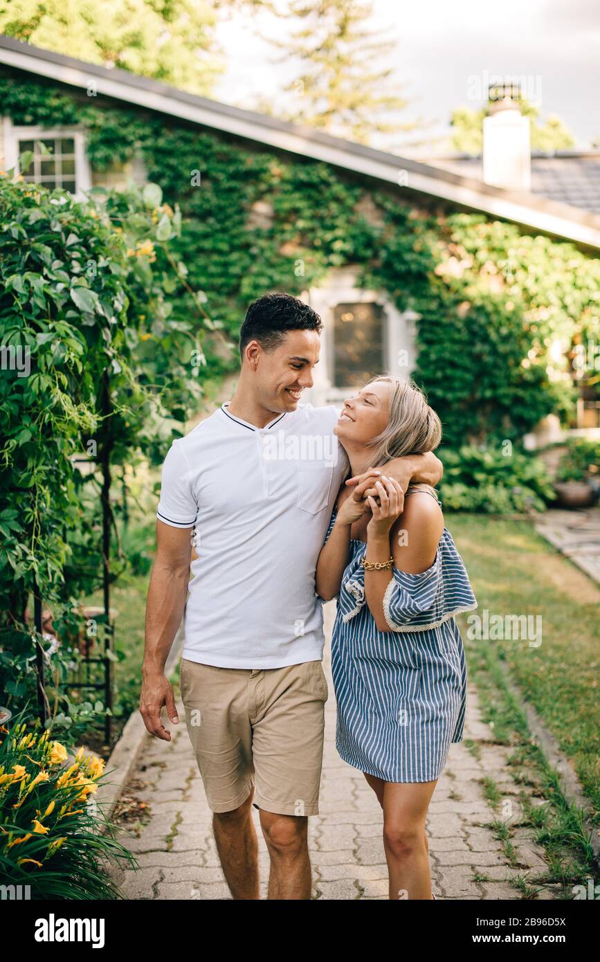 Young couple standing arm in arm outside cottage Stock Photo - Alamy
